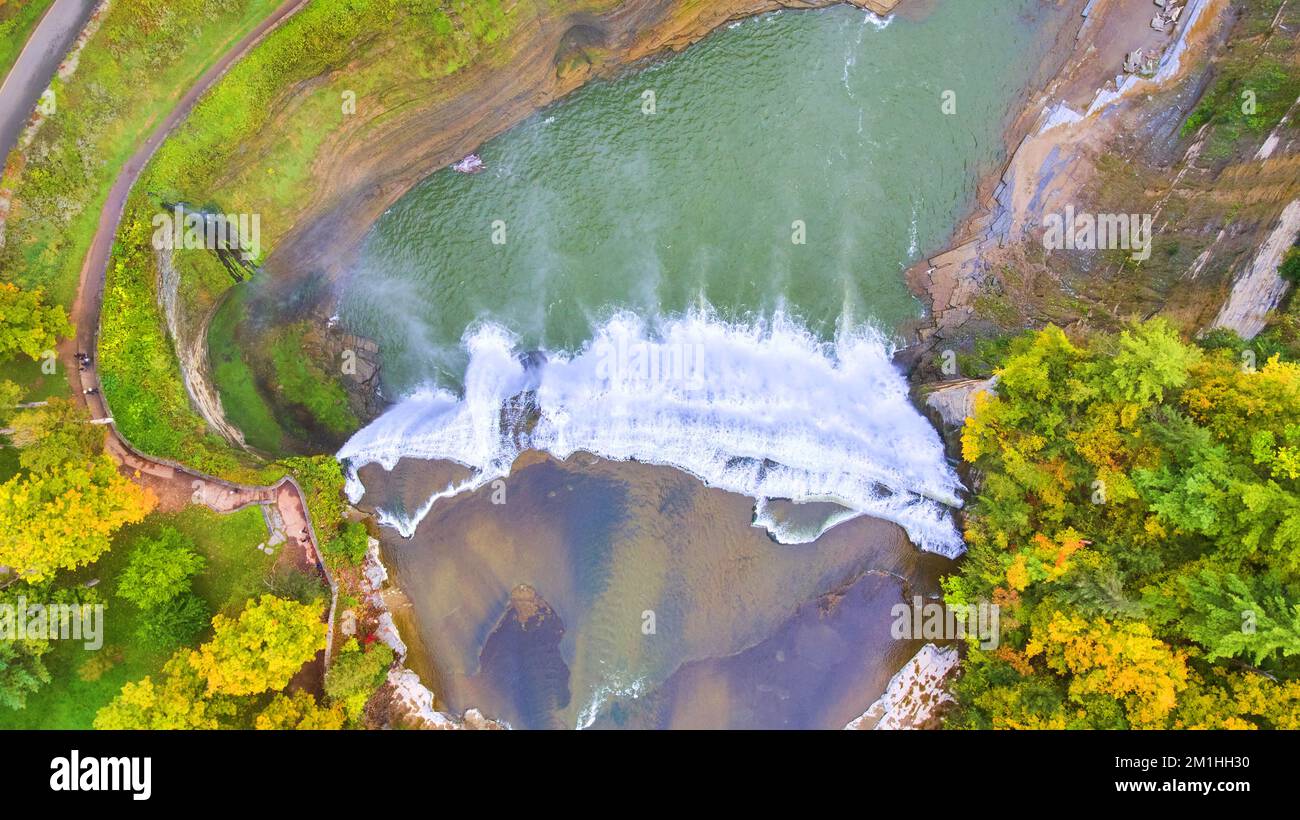 Aerial straight down over huge raging waterfall in canyon with trail ...