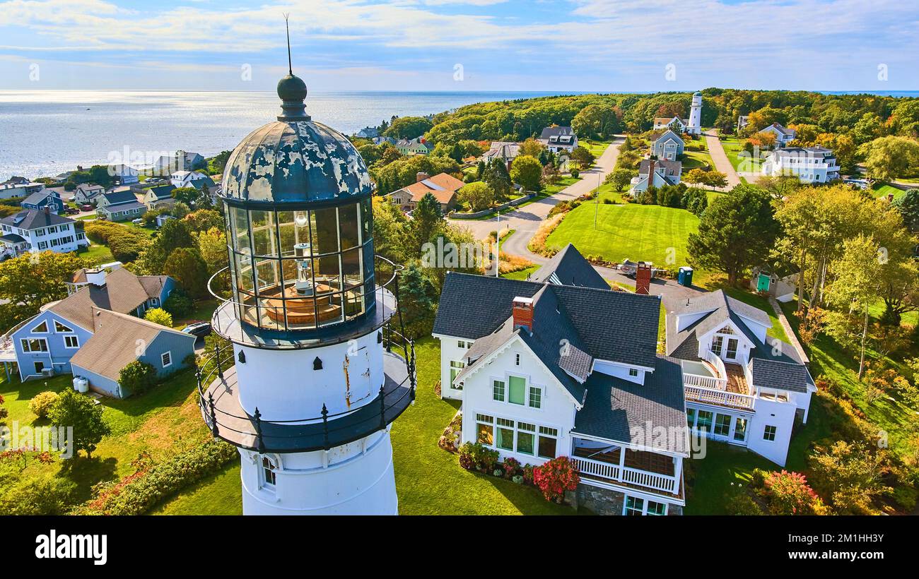 Up close aerial at top of white lighthouse with homes and ocean view in ...