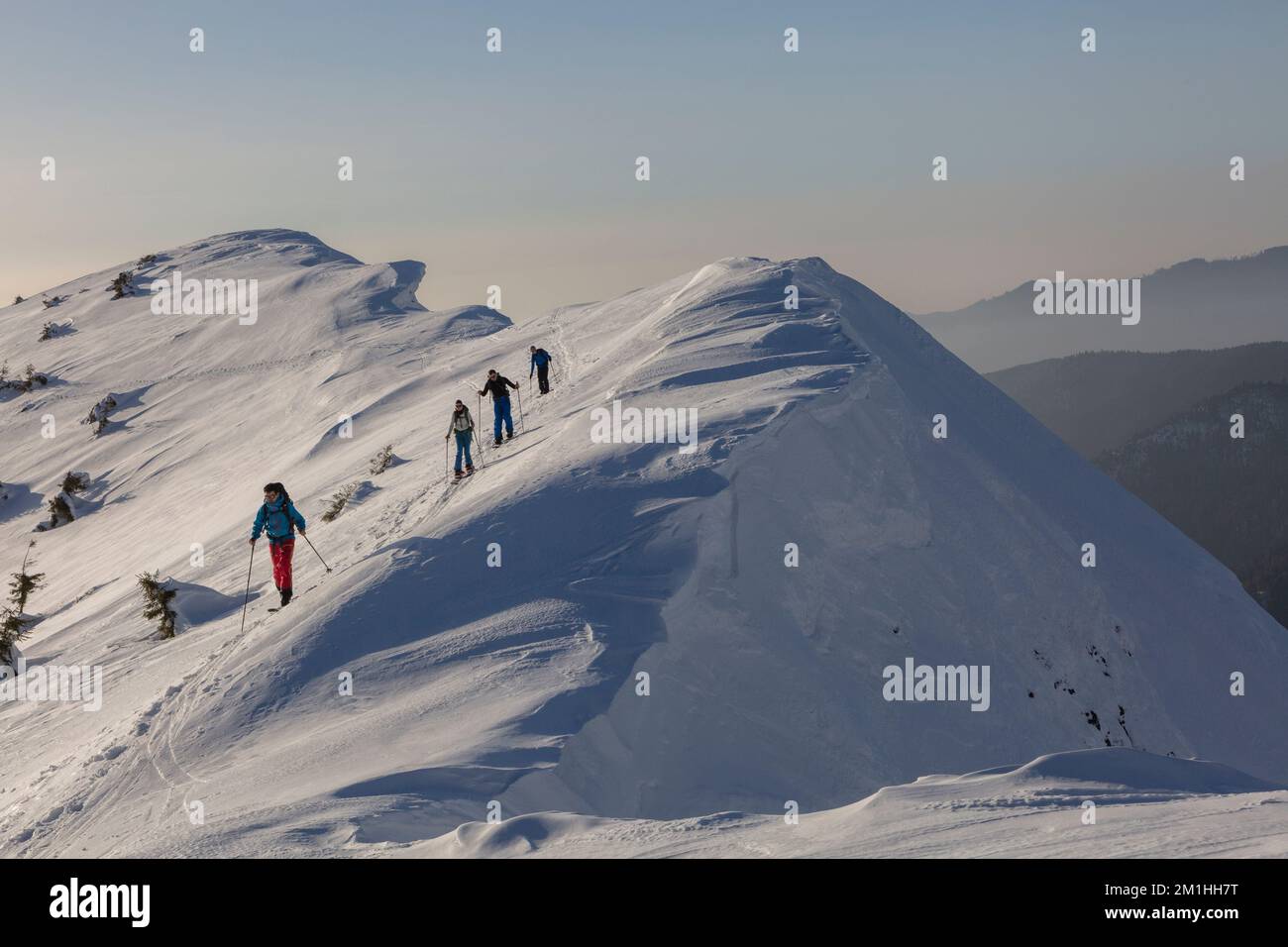 a team of ski tourists is actively climbing up a mountain range with ...