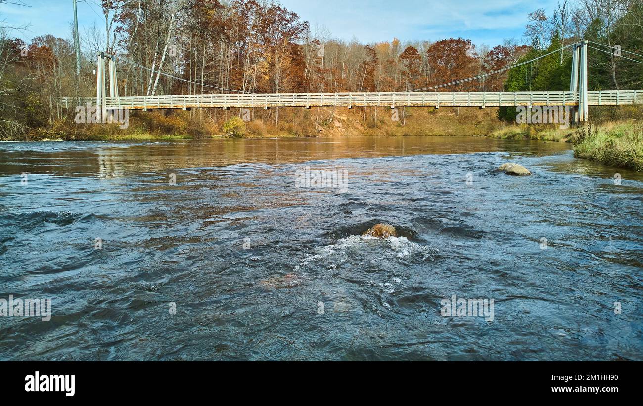 At water level over river with view of suspension bridge in late fall ...