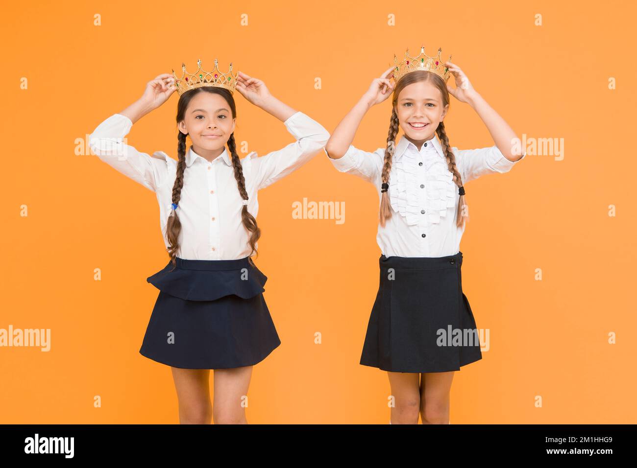 Dreaming about fame and richness. Schoolgirls wear golden crowns symbol ...