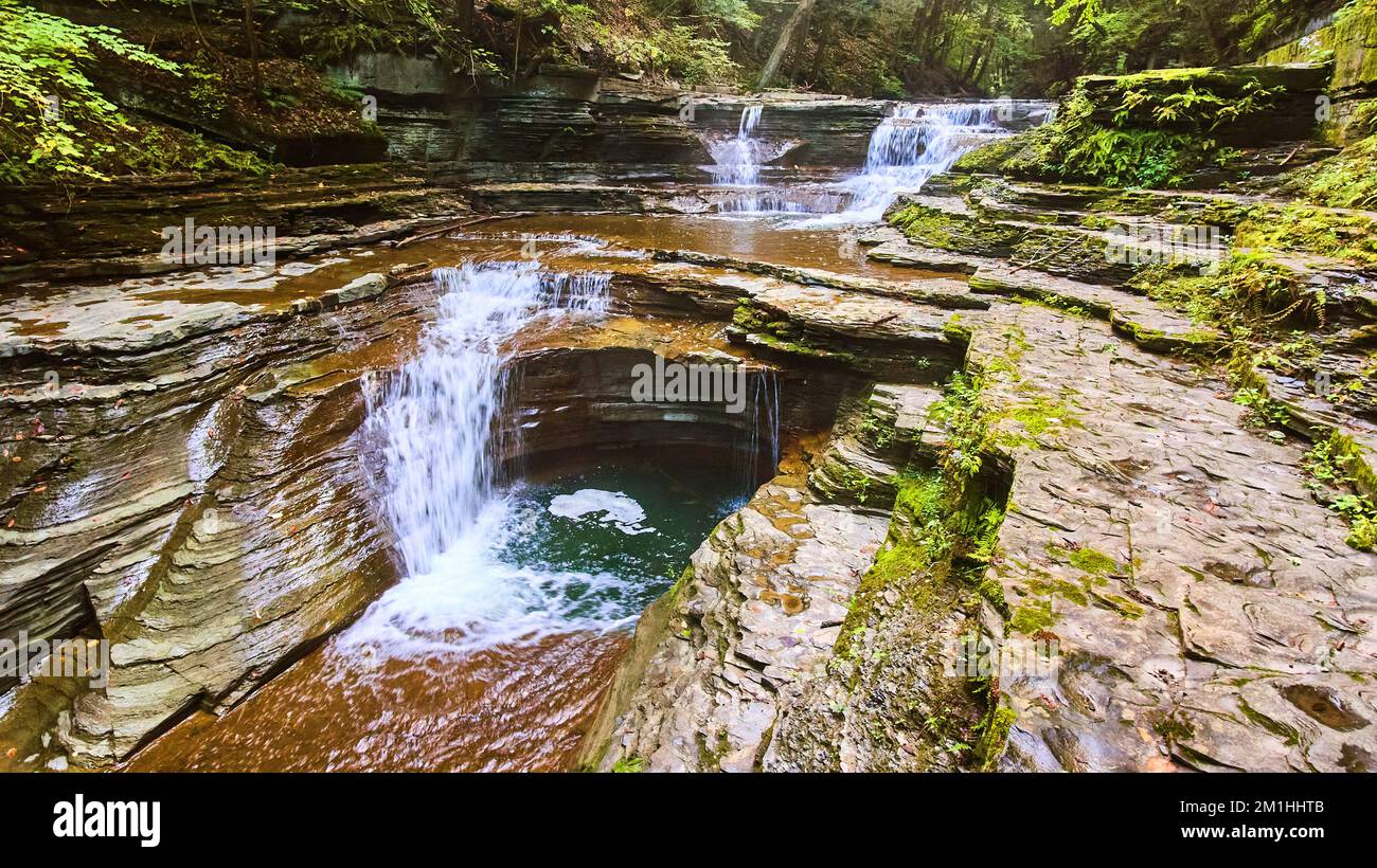Layered rocks and walking path along gorge with pair of waterfalls in ...
