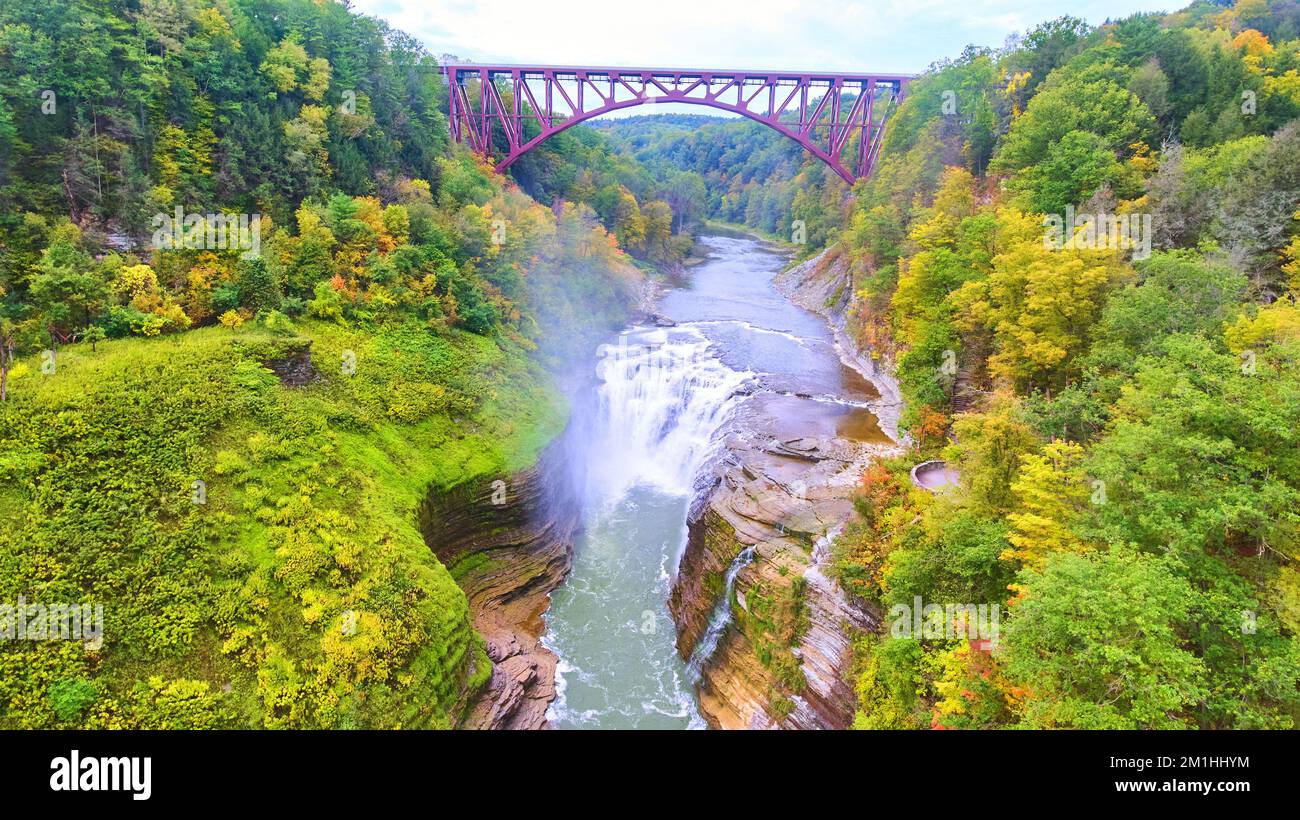 Drone over amazing raging waterfall carving into cliffs with train ...