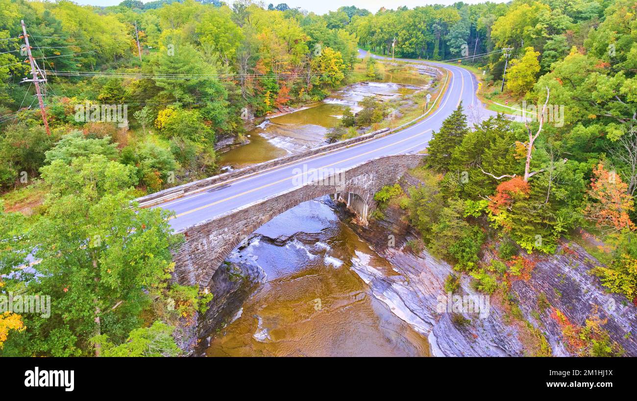 Stone bridge road crosses over bridge in New York fall forest Stock ...