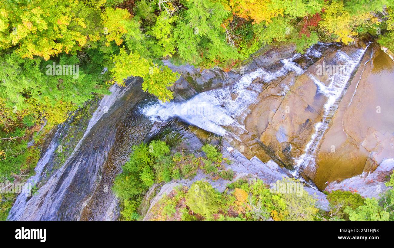 Green forest from above with river and waterfall dropping off into deep ...