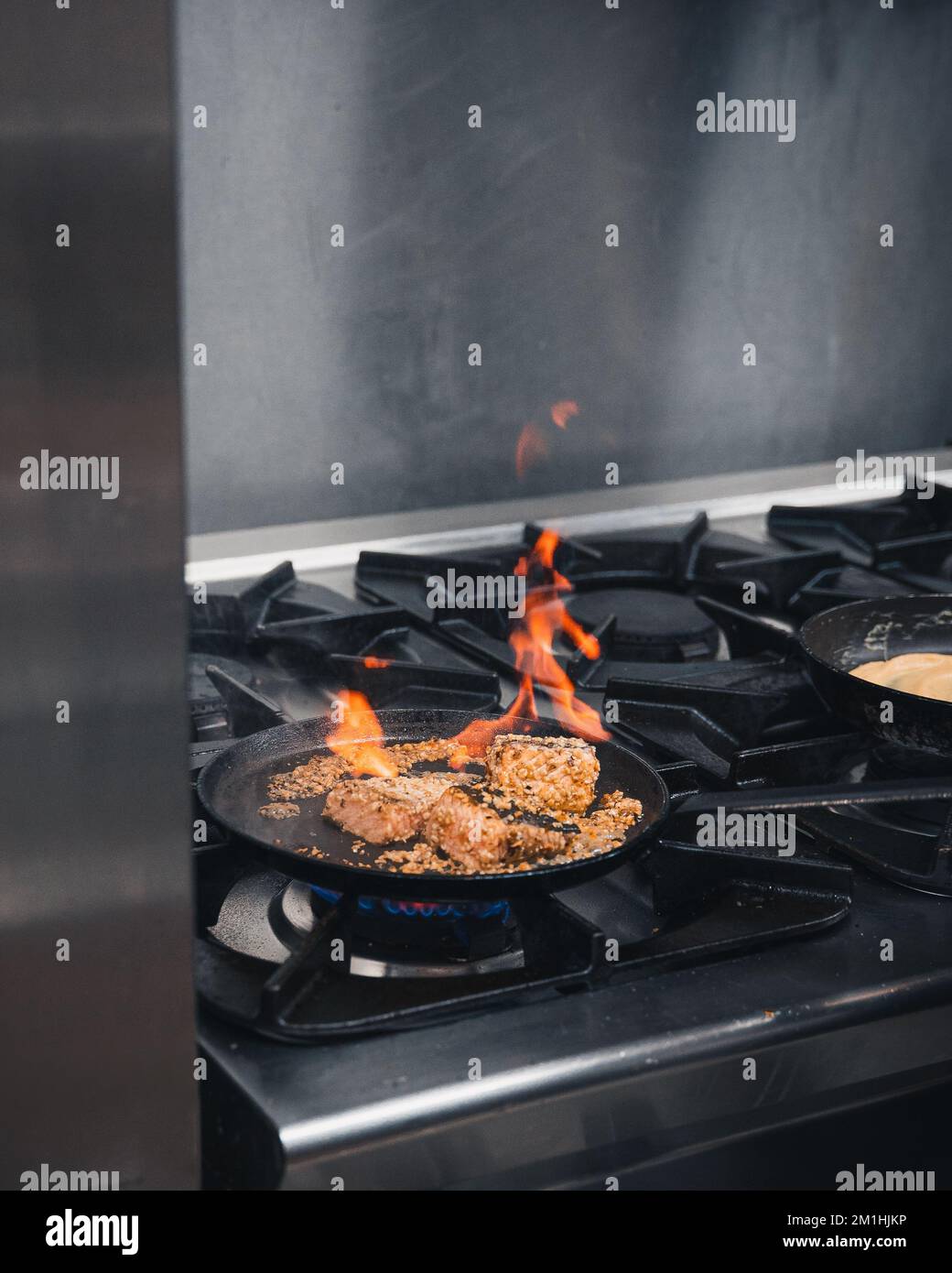 The sizzling salmon cooking in a pan, covered in fire flames on the ...