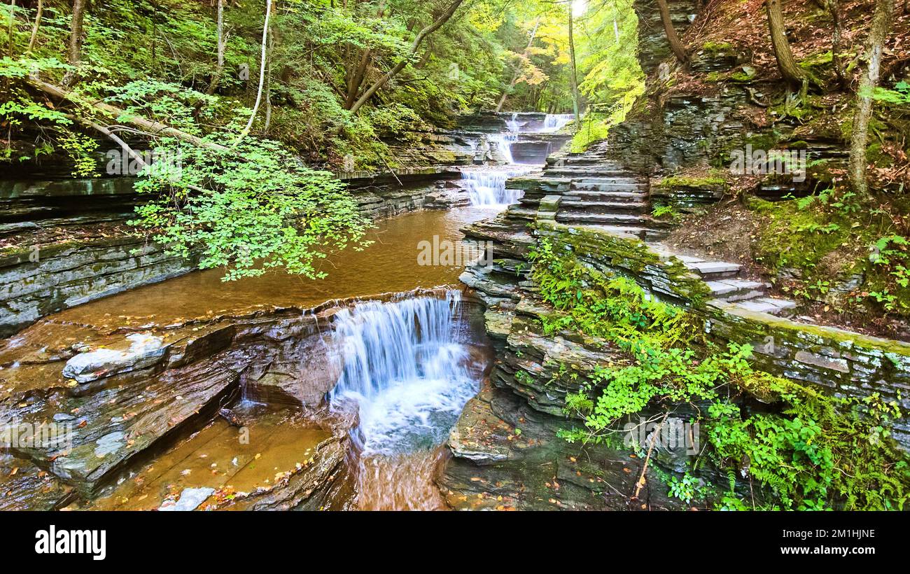 Aerial over Upstate New York gorge and waterfall with stone walking ...