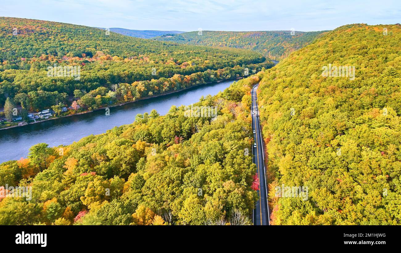 Road cutting through early fall forest along Delaware River from drone ...