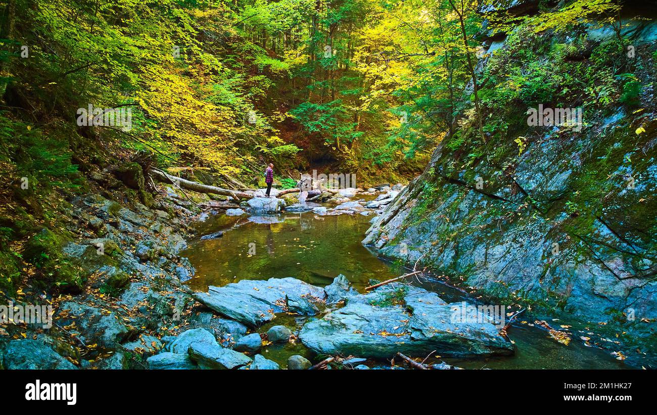 Hiker crossing river by boulders aerial in stunning fall gorge with ...