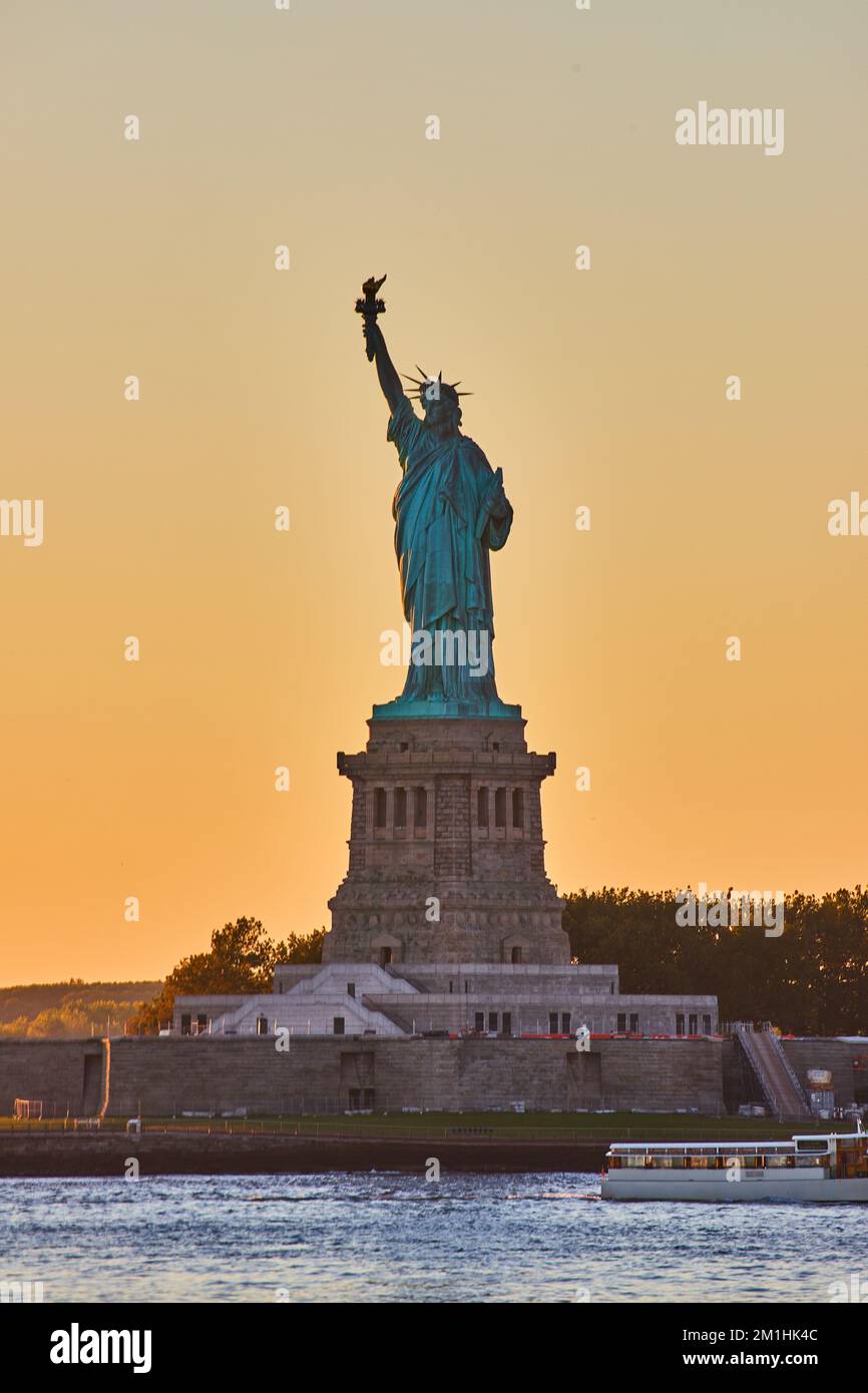 New York City golden hour light around iconic Statue of Liberty in dusk ...