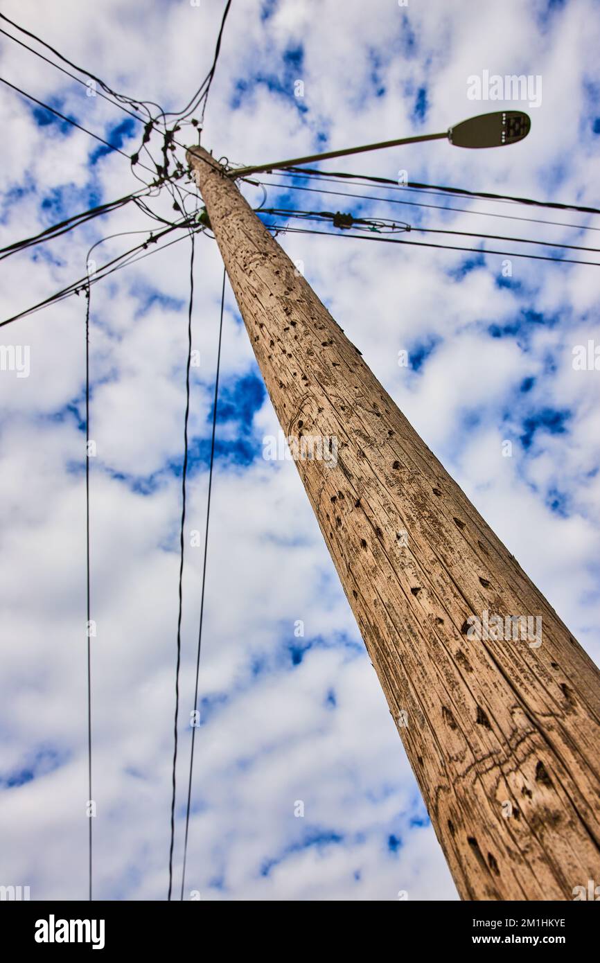 Detail looking up textured wood telephone pole with spotty clouds on ...