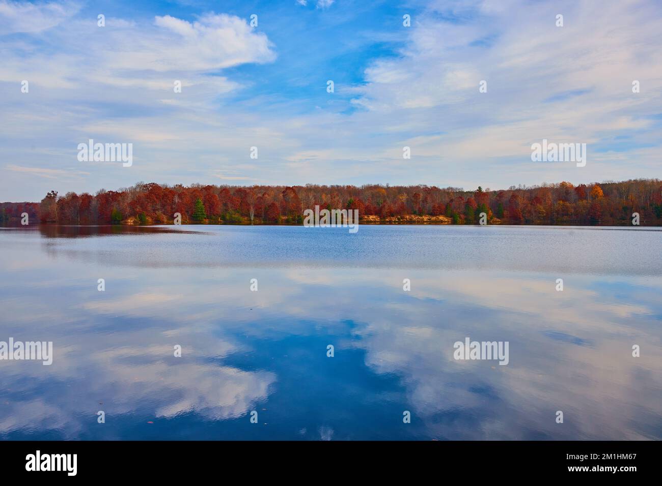 Crystal clear lake surface with fall forests lining the coast in ...