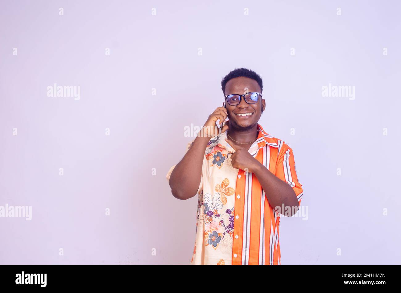 young black African boy standing on a white studio wall making calls ...