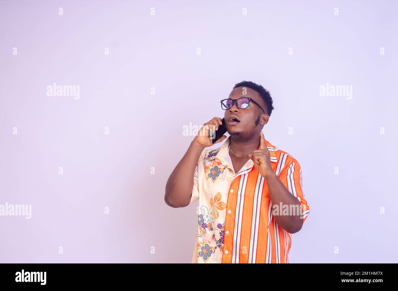 young black African boy standing on a white studio wall making calls ...
