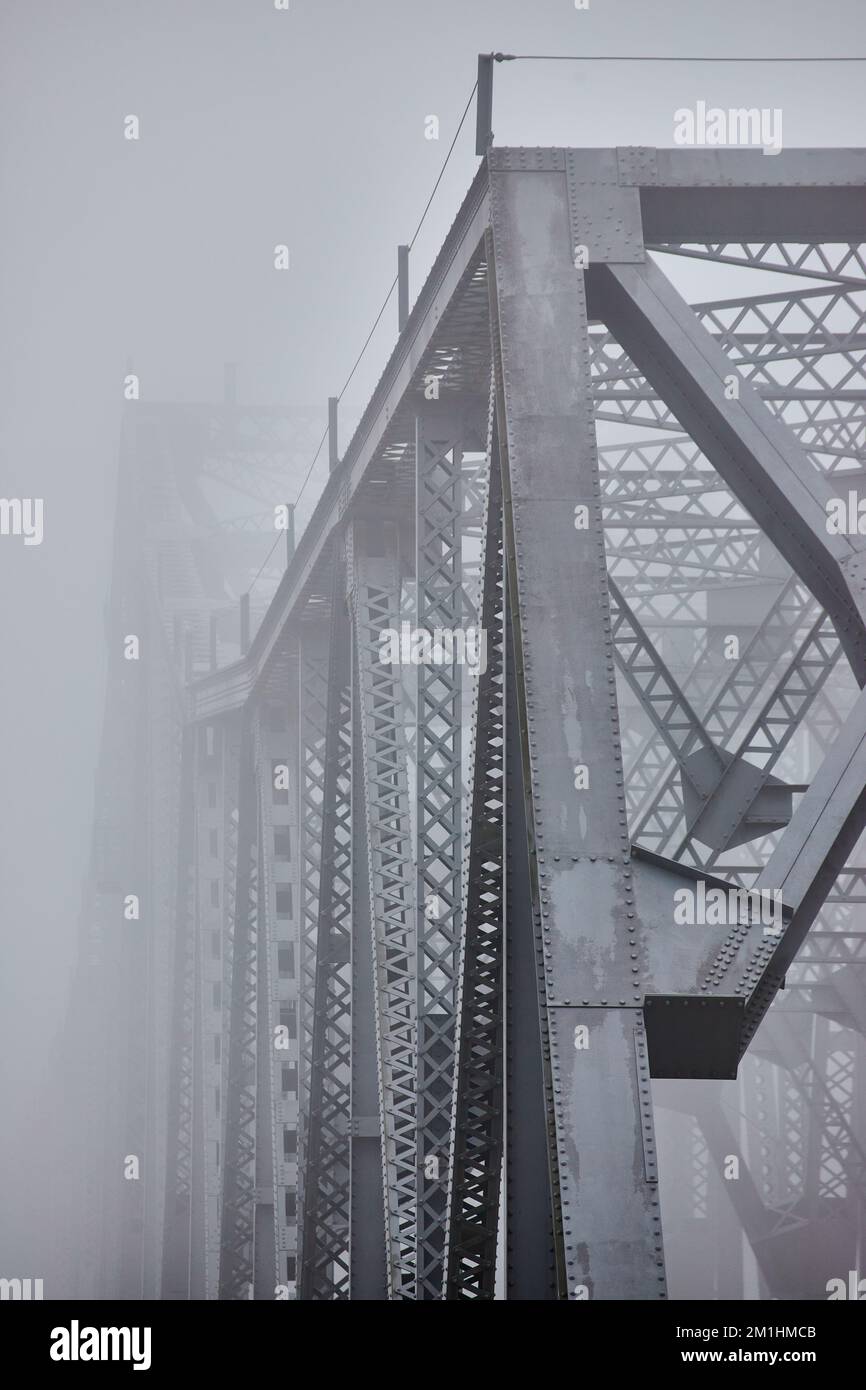 Vertical looking down large steel bridge fading away on fogging morning ...