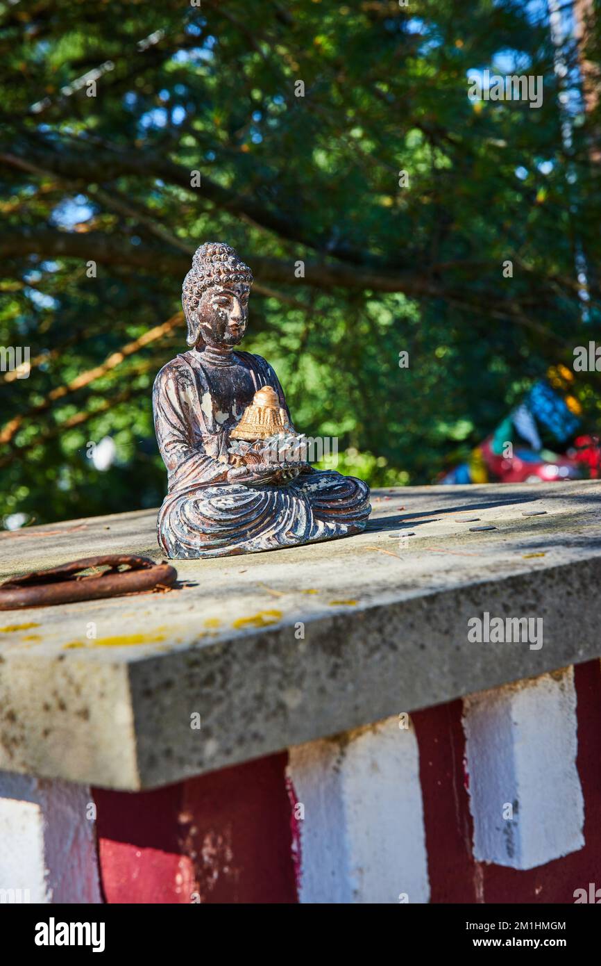 Cement square with small Buddhist statue resting on top Stock Photo - Alamy