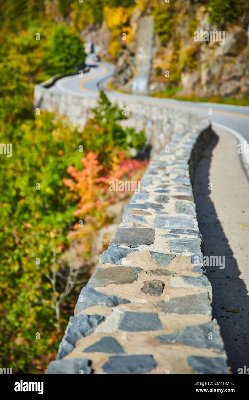 Beautiful stone wall winding along road that zig zags through mountain ...