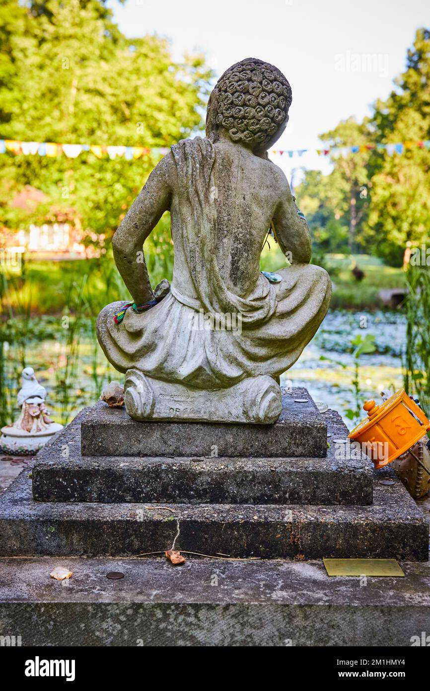 Tibetan Mongolian Buddhist stone statue from behind overlooking lily ...