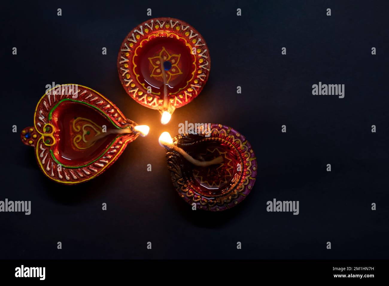 Happy Diwali. Three clay dia lamps are burning on a black background ...