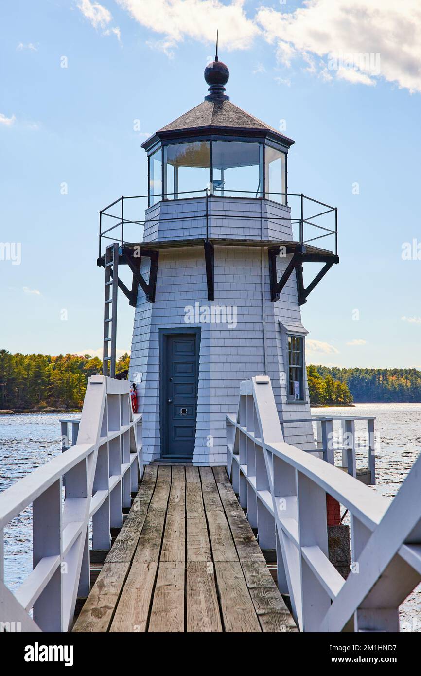 Boardwalk with railing leads to small white lighthouse on Maine river ...