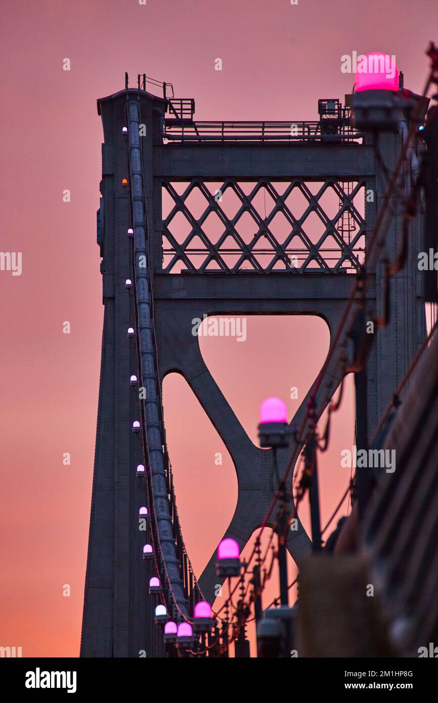 Pink lights in detail on support wires of American bridge with golden ...