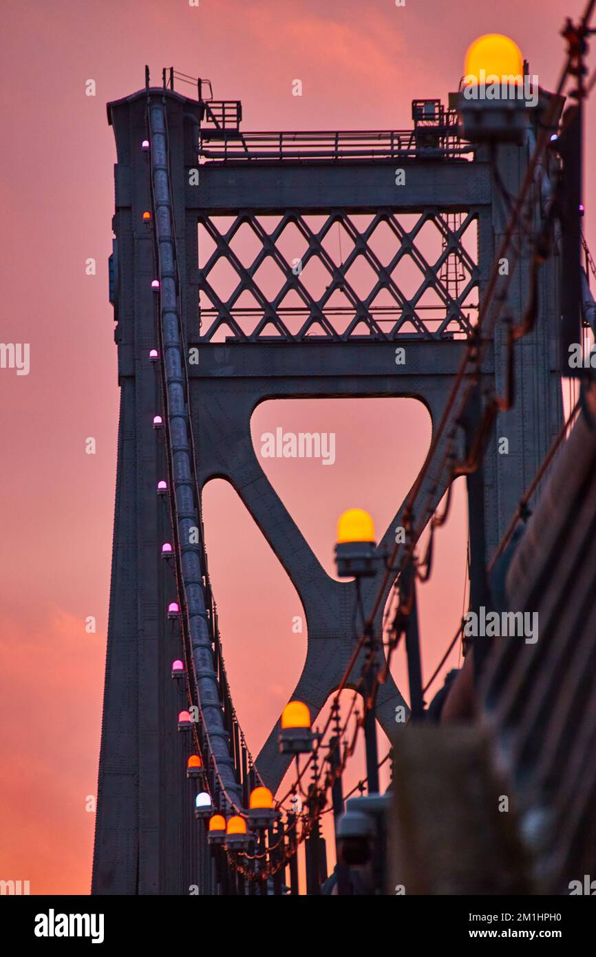 Orange lights in detail on support wires of American bridge with golden ...