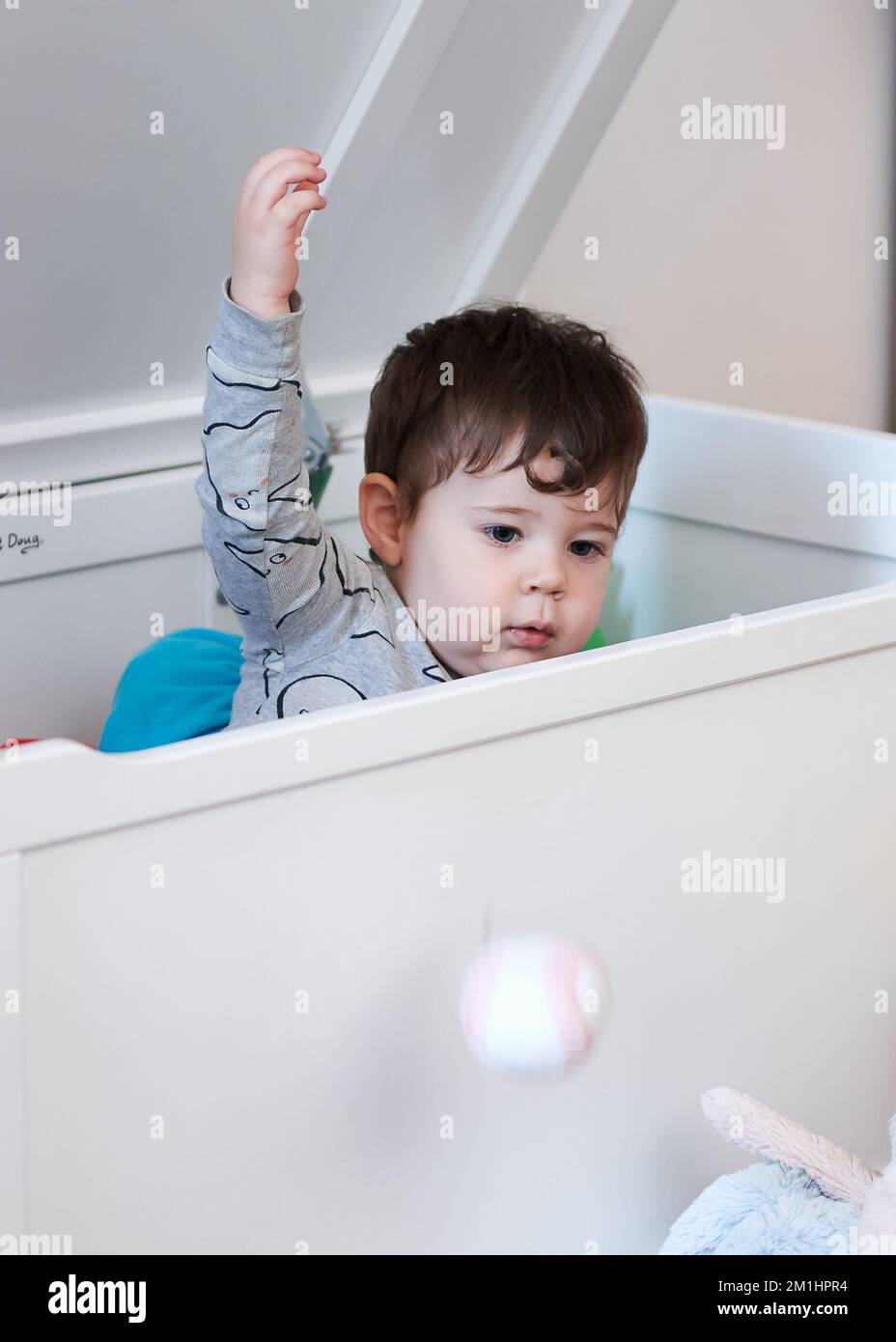cute little boy throwing toys out of the toy box while sitting inside ...