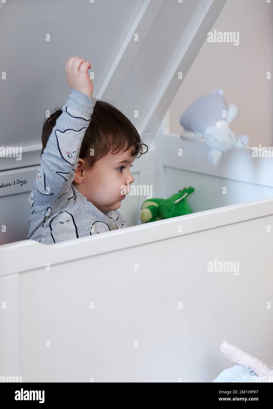 cute little boy throwing toys out of the toy box while sitting inside ...