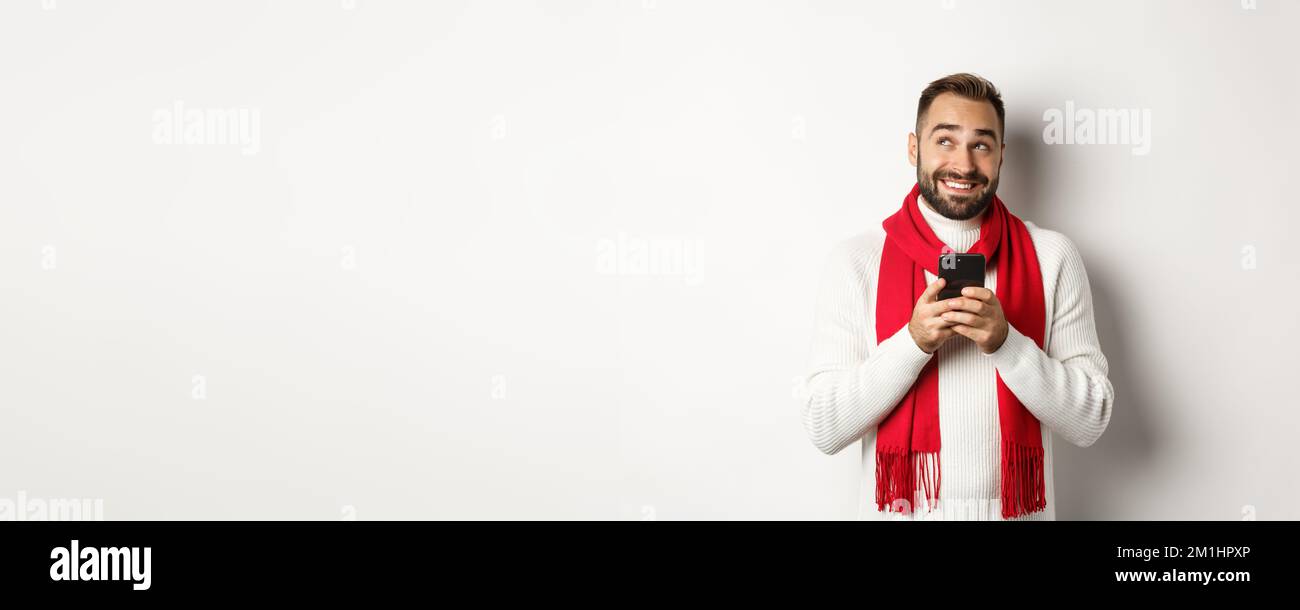 Man thinking while texting message on mobile phone, smiling and ...