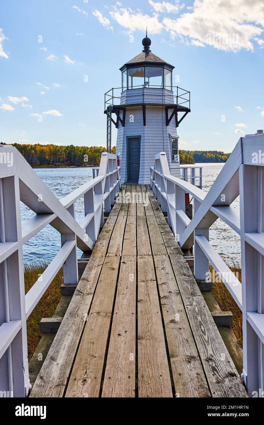 Wood boardwalk with white railing leading to small Maine lighthouse ...