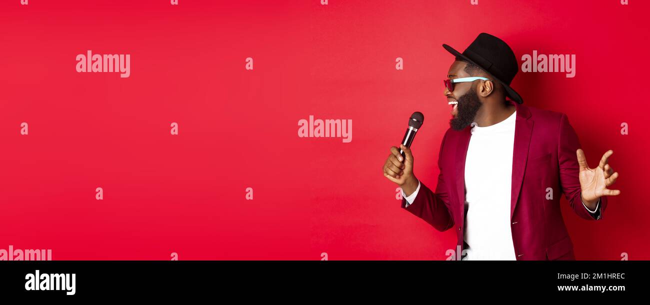 Passionate black male singer performing against red background, singing ...
