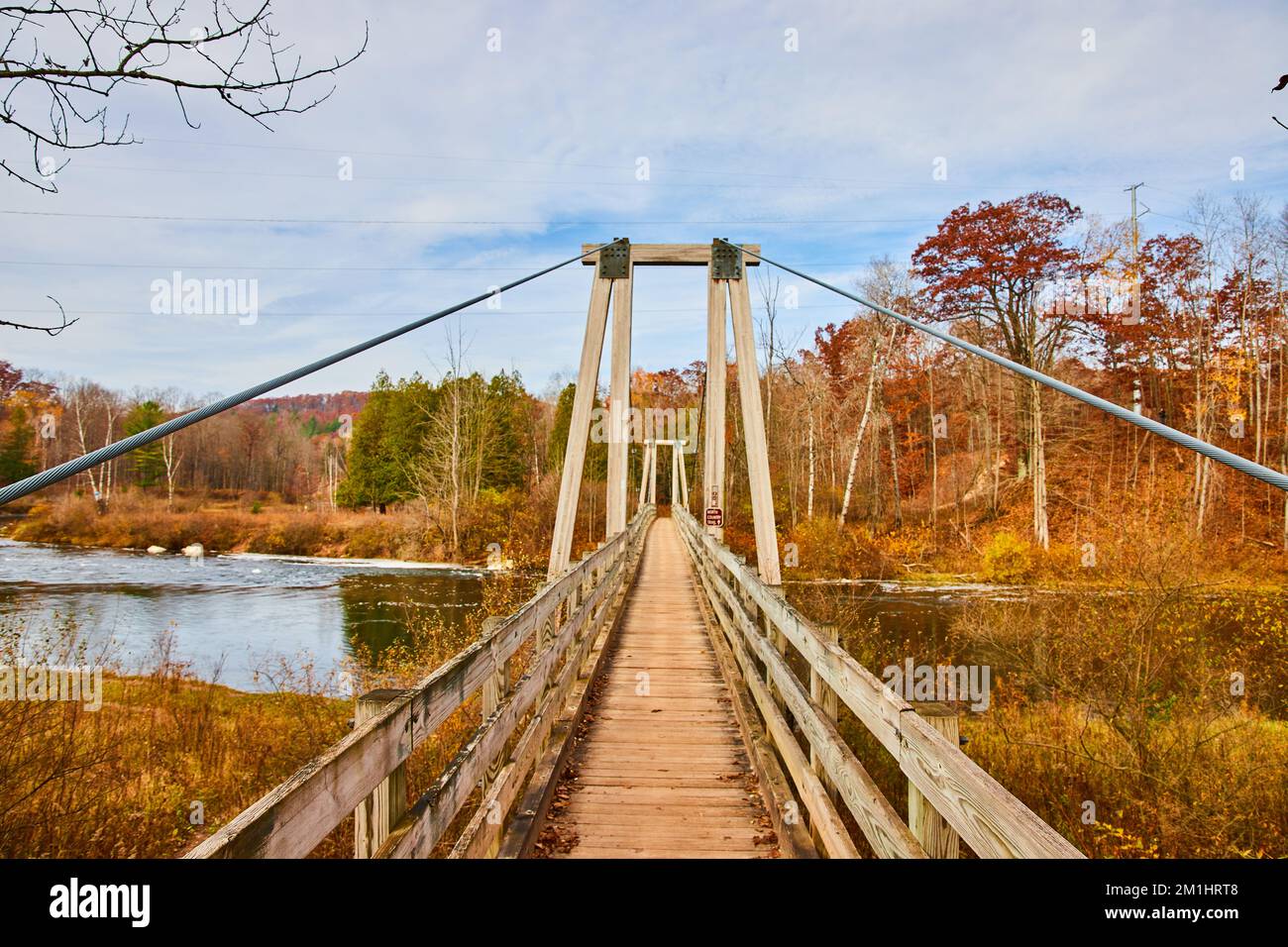 Walking down suspension bridge along river with fall foliage around ...