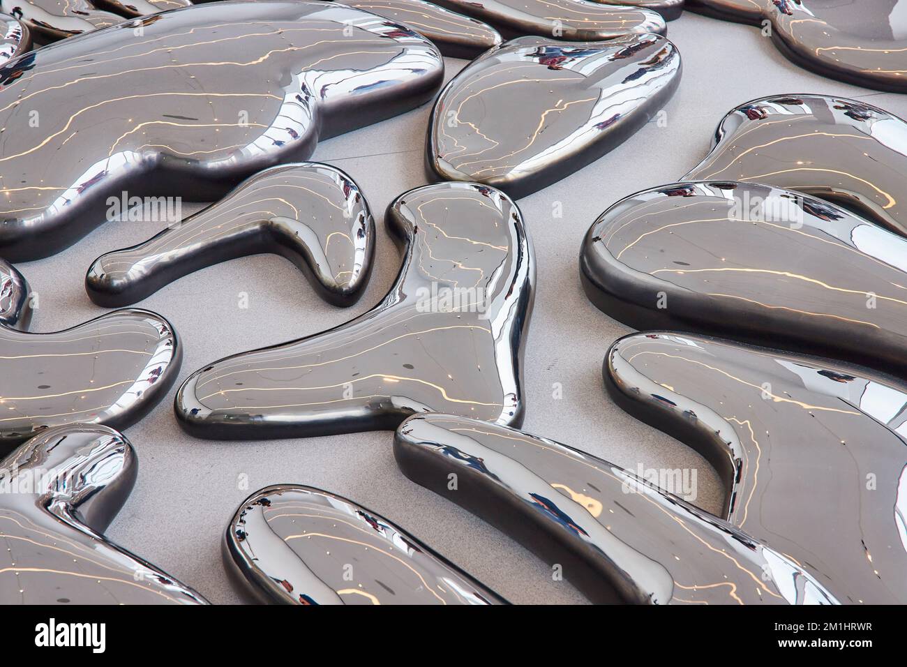 Detail of reflecting metal shapes melting on ground of art exhibit ...