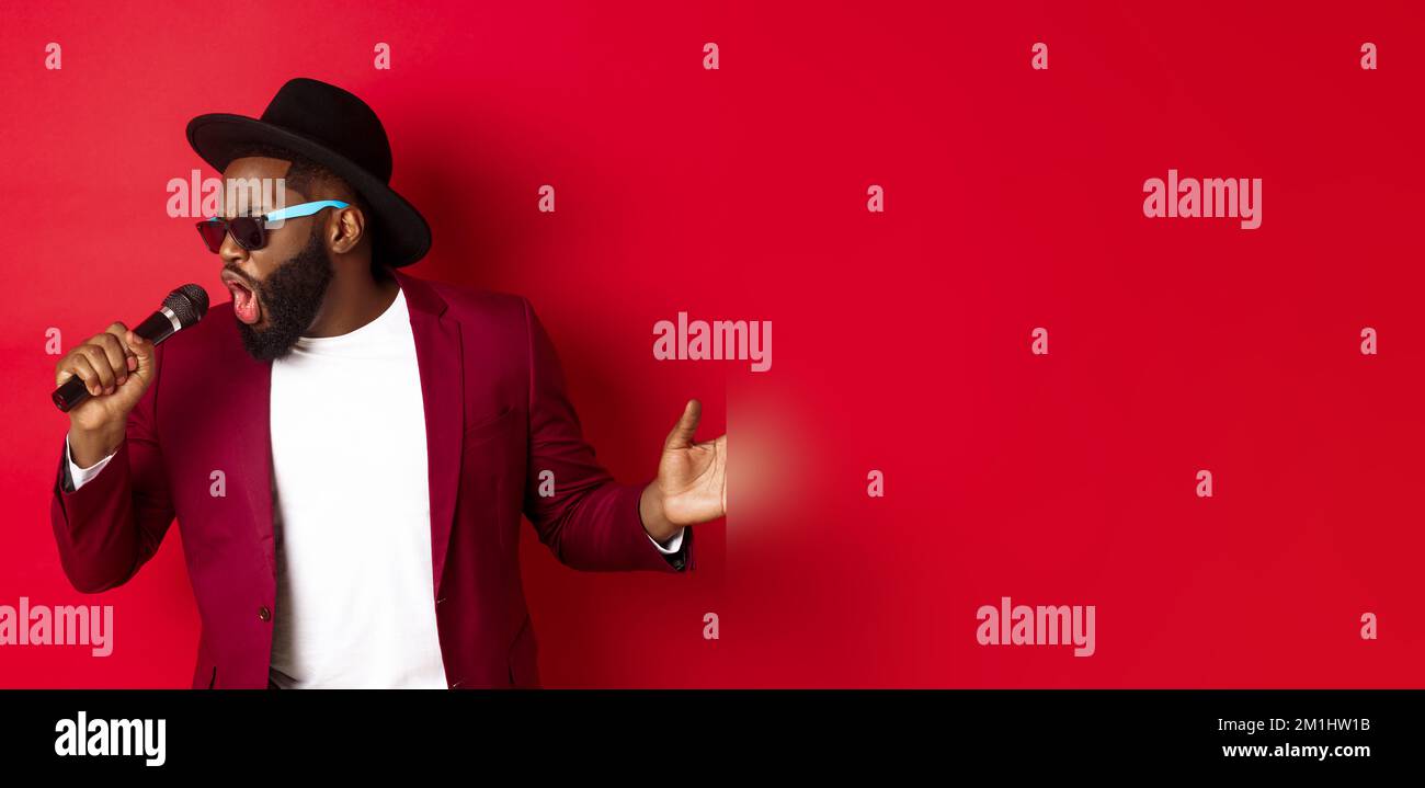 Passionate black male singer performing against red background, singing ...