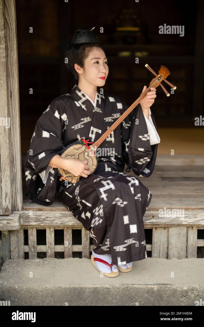Okinawan woman wearing traditional kimono playing the 3-stringed ...