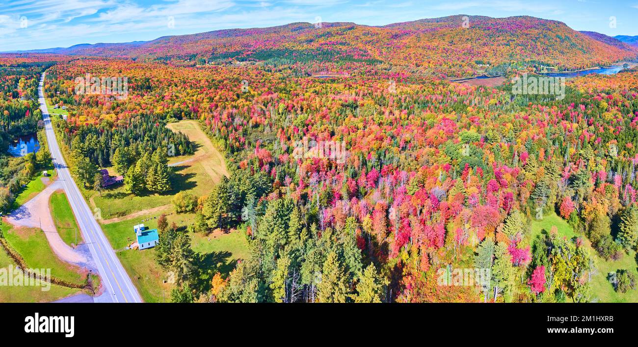 Aerial over road going through beautiful hills of peak fall foliage ...
