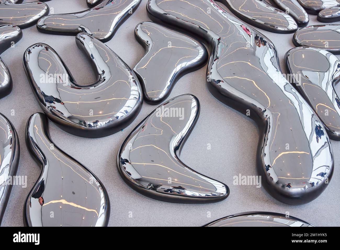 Ground covered in large melted reflecting metal shapes in exhibit Stock ...