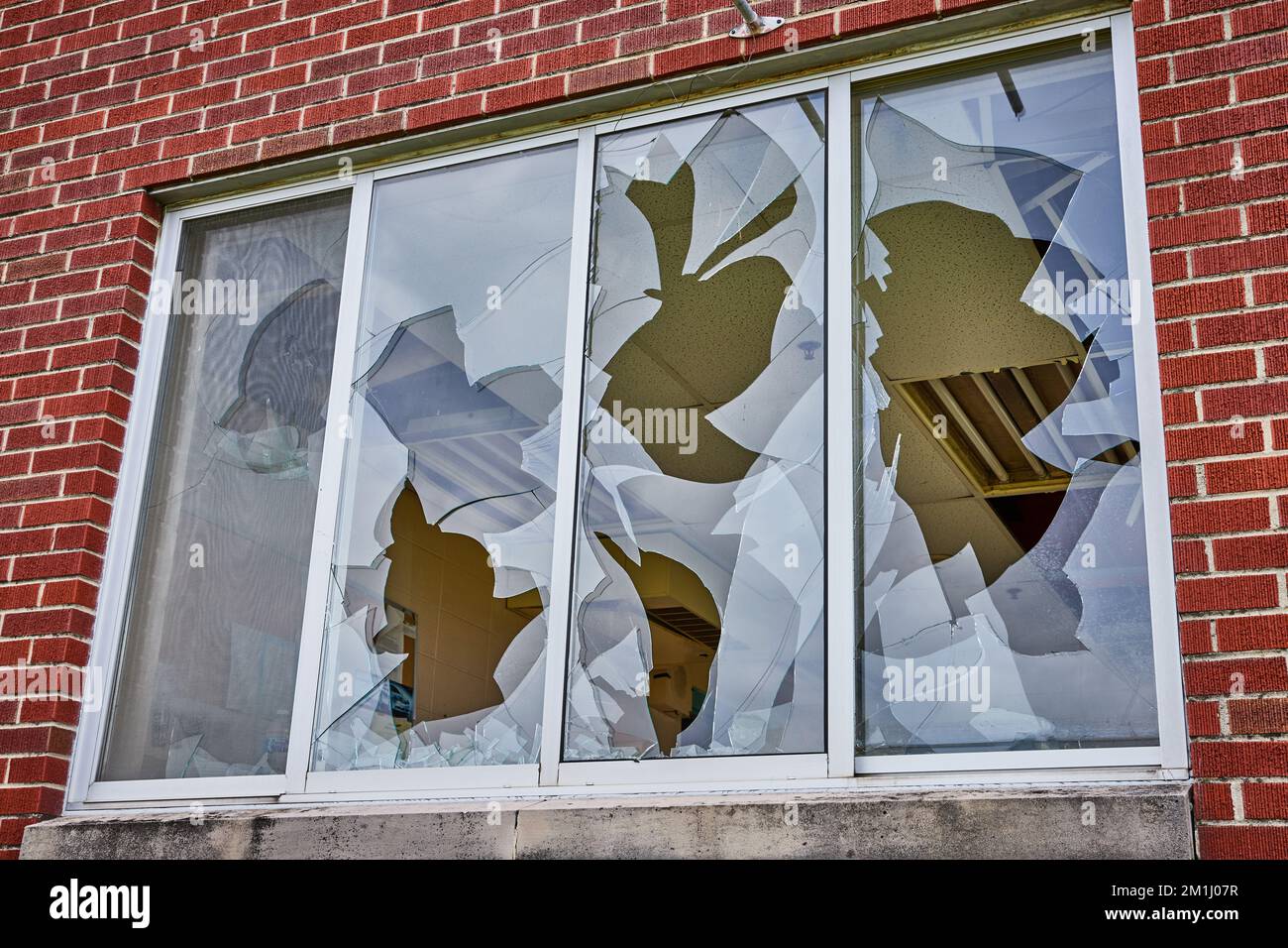 Detail of layers of broken glass on window outside with brick wall ...