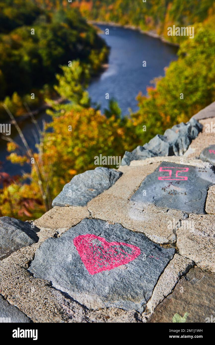 Detail stone wall with pink heart chalk art and soft river with fall ...