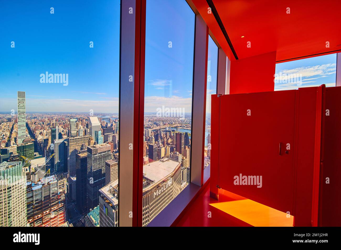 Surreal orange bathroom stall with windows overlooking New York City ...