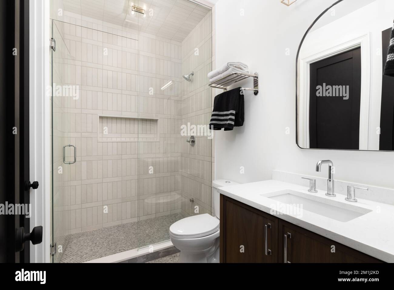 A bathroom with a wooden vanity cabinet and a brown tiled brown shower ...