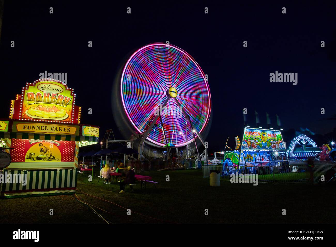 County fair ferris wheel with purple lights and carnival vendors Stock ...
