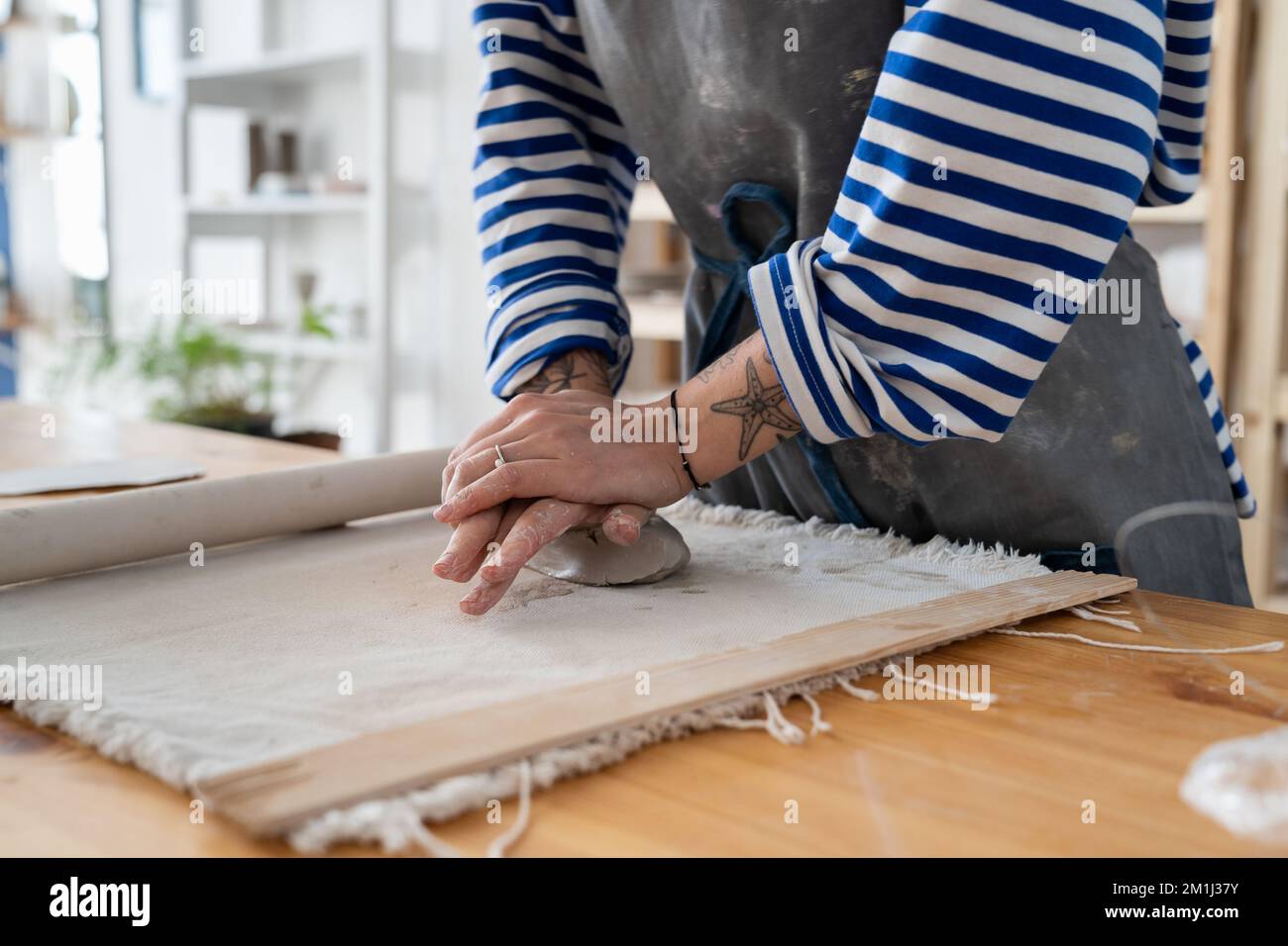 Closeup of woman ceramist in dirty apron molding raw clay for shaping ...
