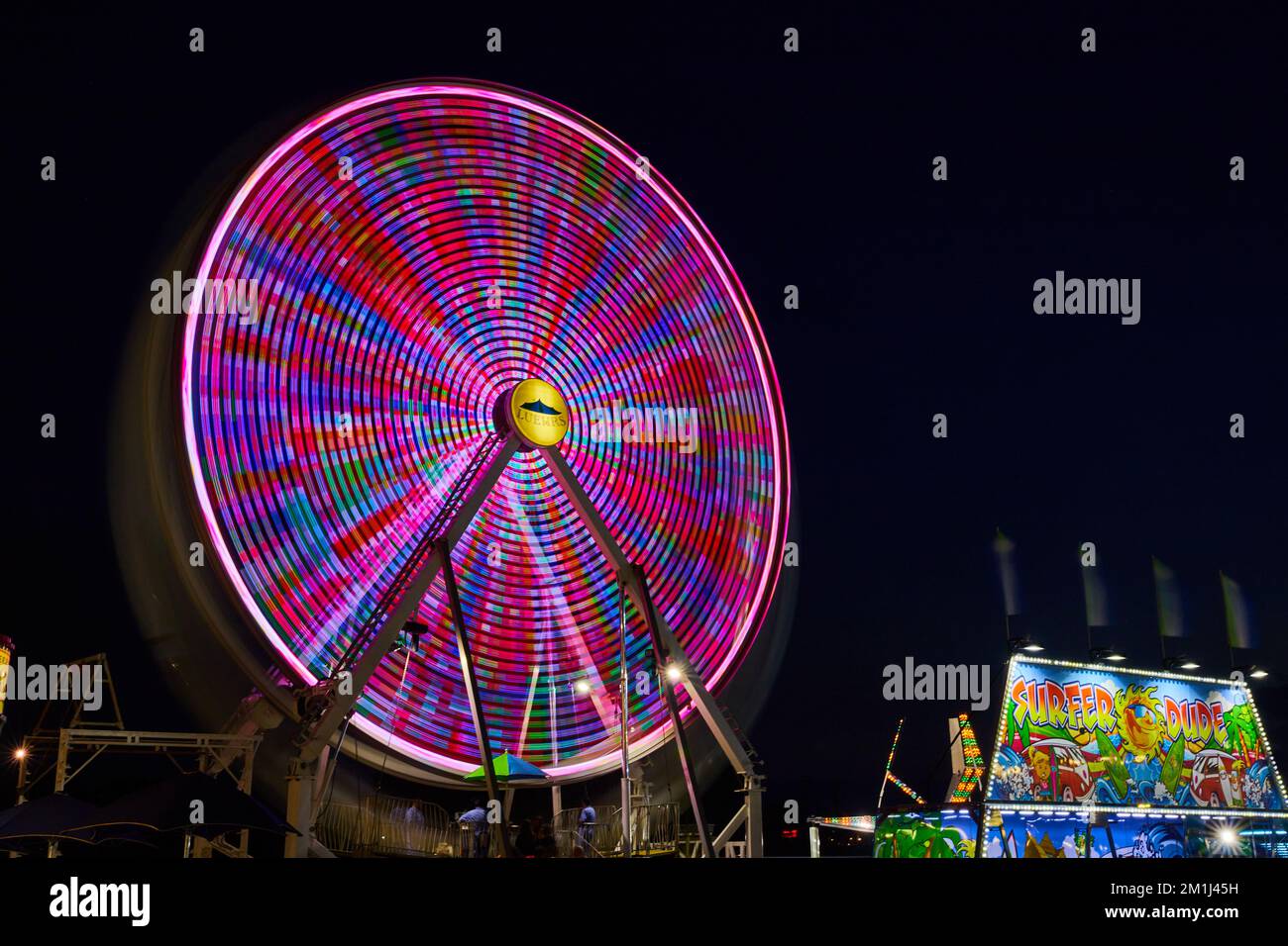Full purple ferris wheel at night with vendors for carnival county fair ...