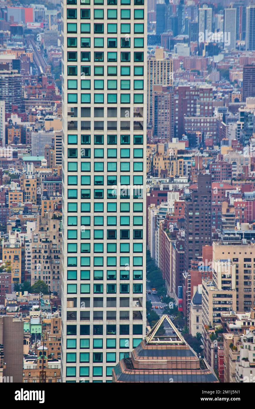 Tall narrow skyscraper of turquoise squares with background of small ...