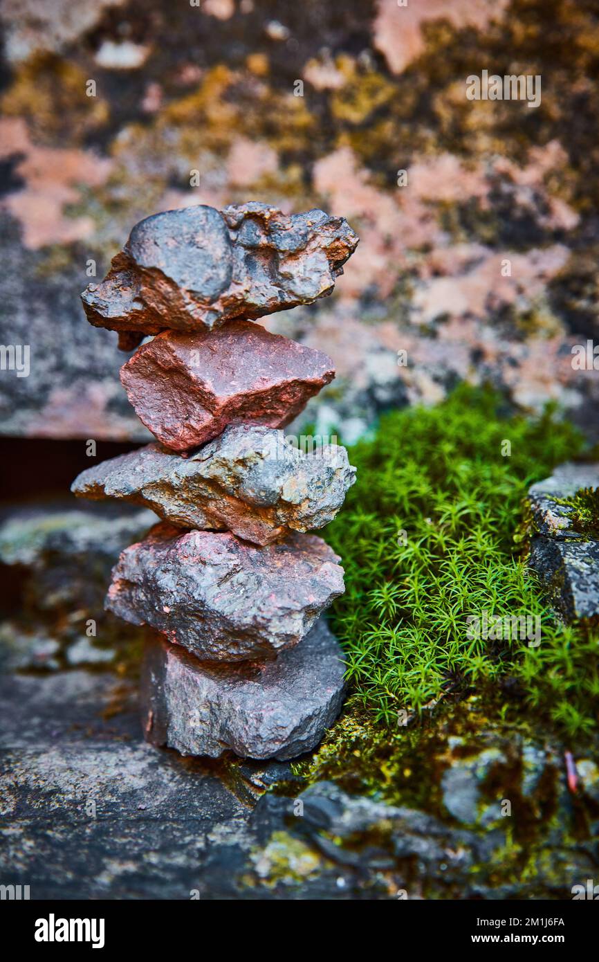 Focus on cairn stone stack of tiny rocks nested against mossy rocks and ...