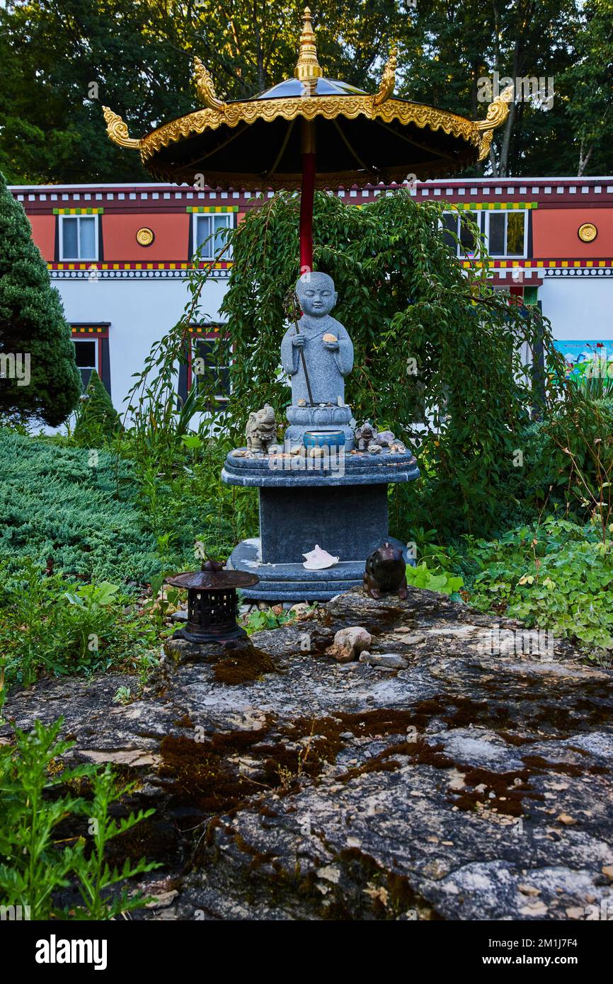 Religious statue in garden with golden umbrella Stock Photo - Alamy
