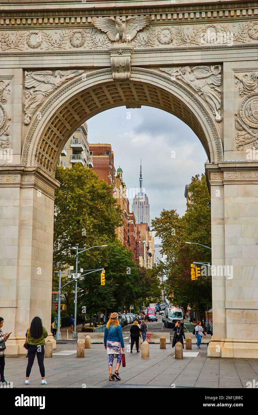 View through Washing Square Park limestone arch with tourists and ...