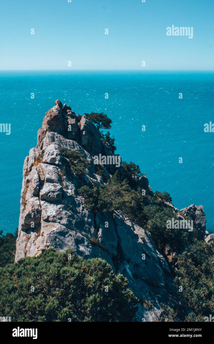 Large rock with green forest around Stock Photo - Alamy