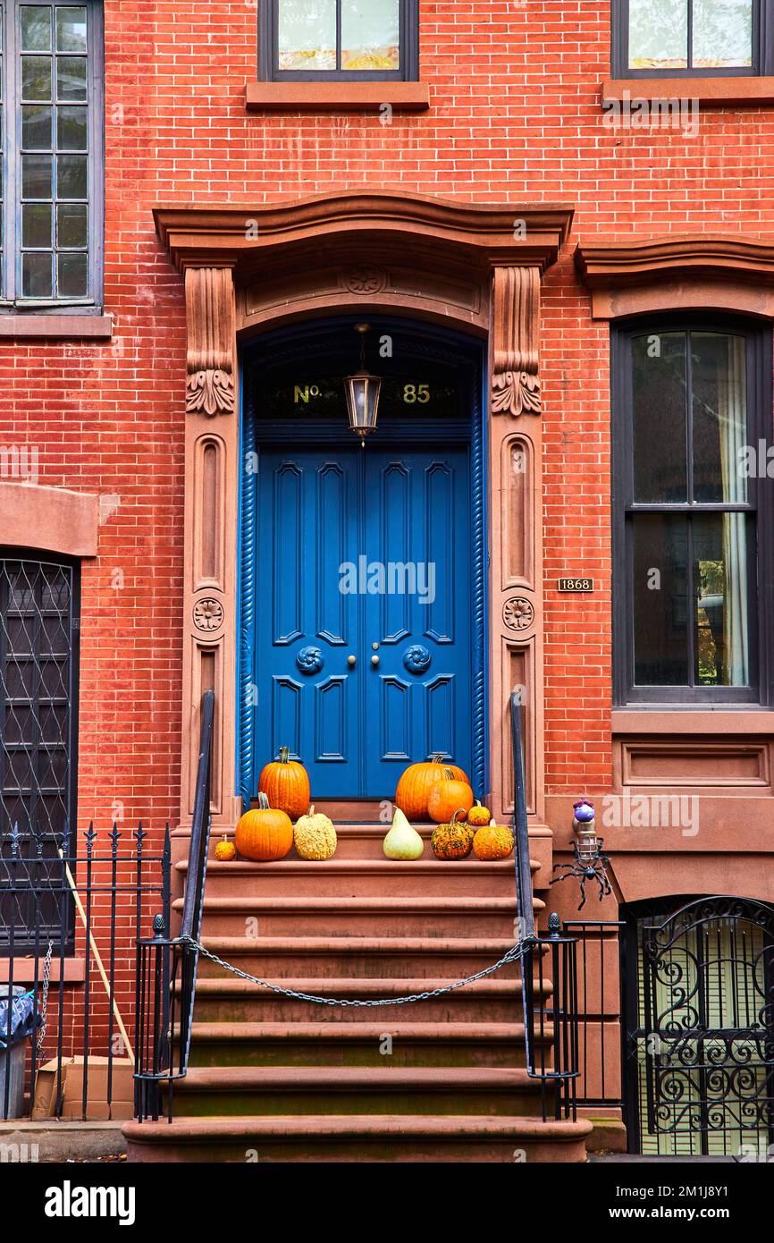 Brick apartment building with steps to blue door and pumpkins straight ...